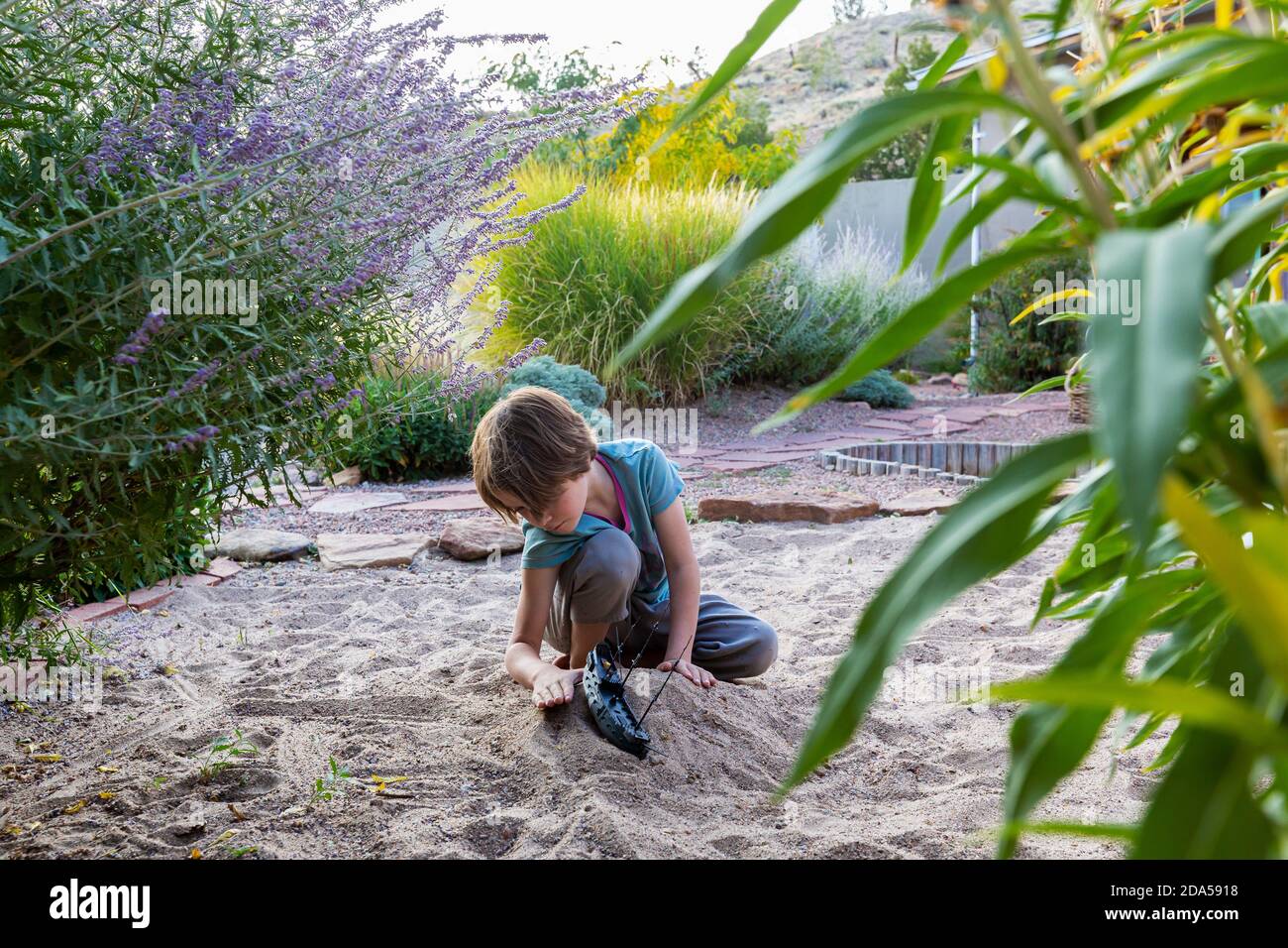 7 year old boy playing in sandy garden with his toy ship Stock Photo ...
