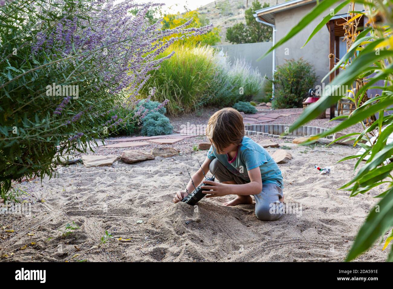 7 year old boy playing in sandy garden with his toy ship Stock Photo ...