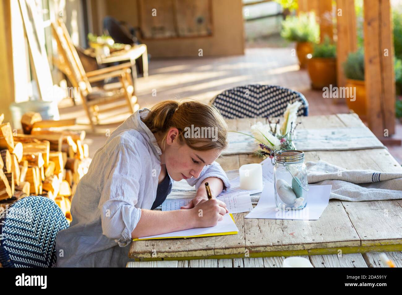 Teenage girl writing outside on terrace at sunset Stock Photo - Alamy
