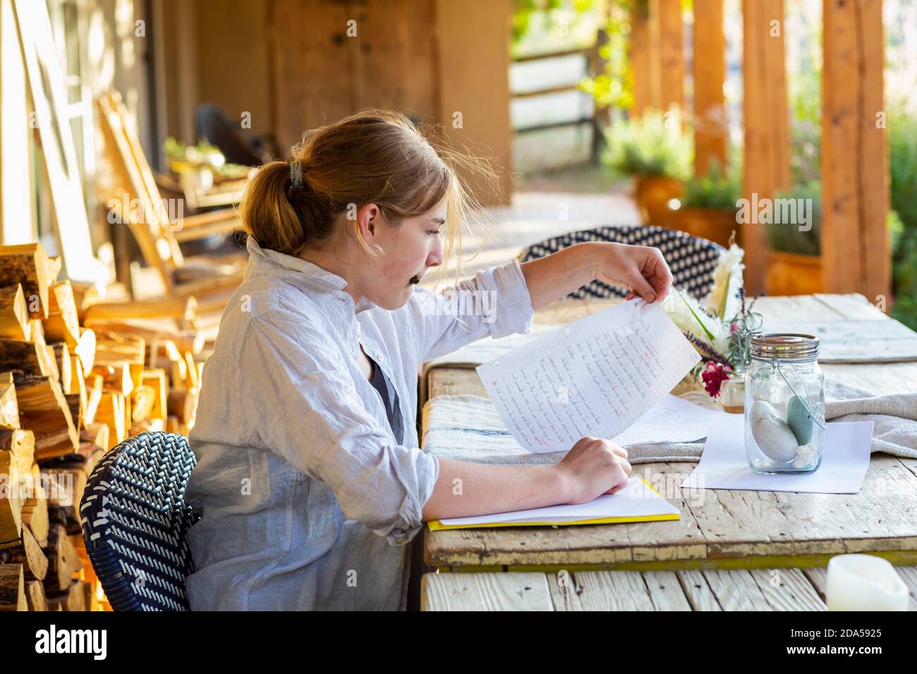 Teenage girl writing outside on terrace at sunset Stock Photo - Alamy