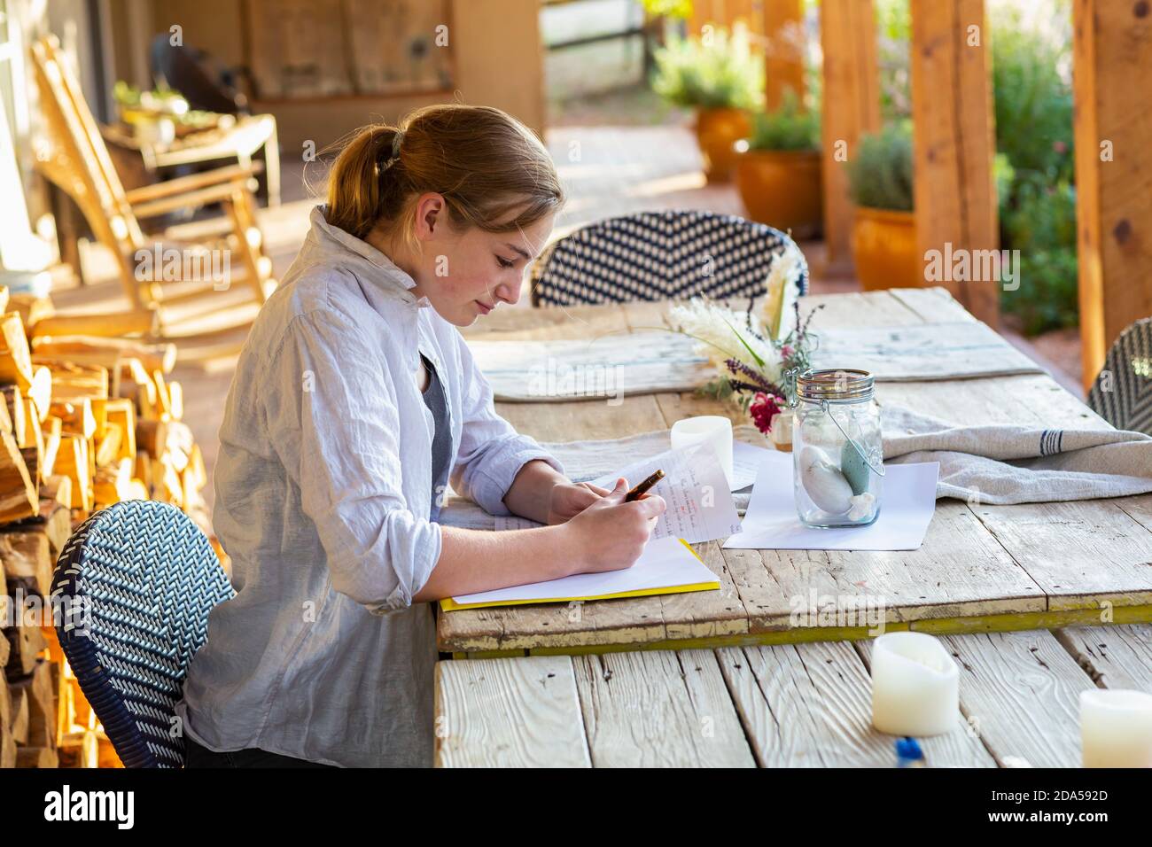 Teenage girl writing outside on terrace at sunset Stock Photo - Alamy