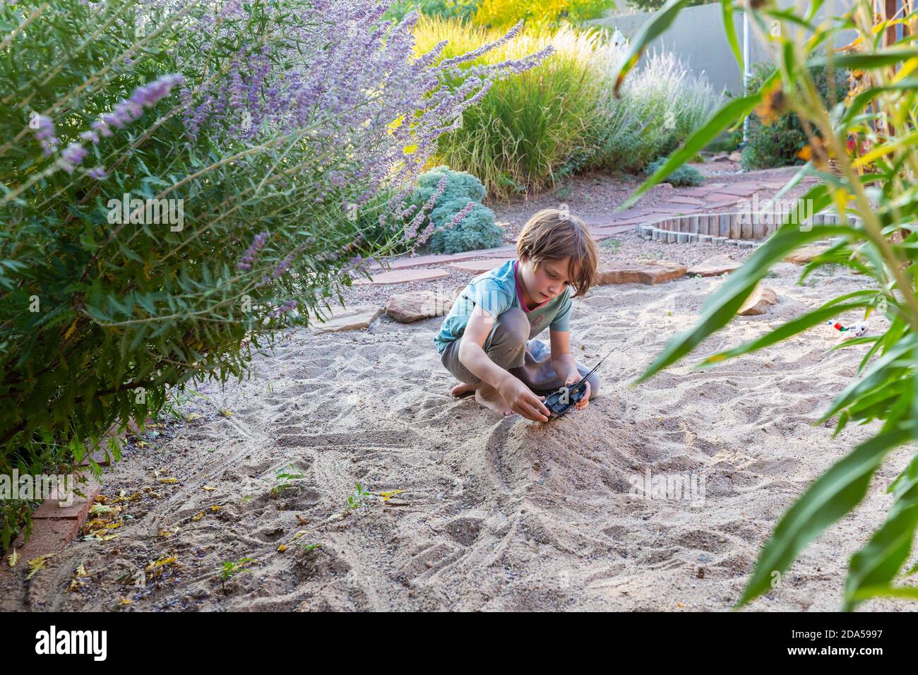 7 year old boy playing in sandy garden with his toy ship Stock Photo ...
