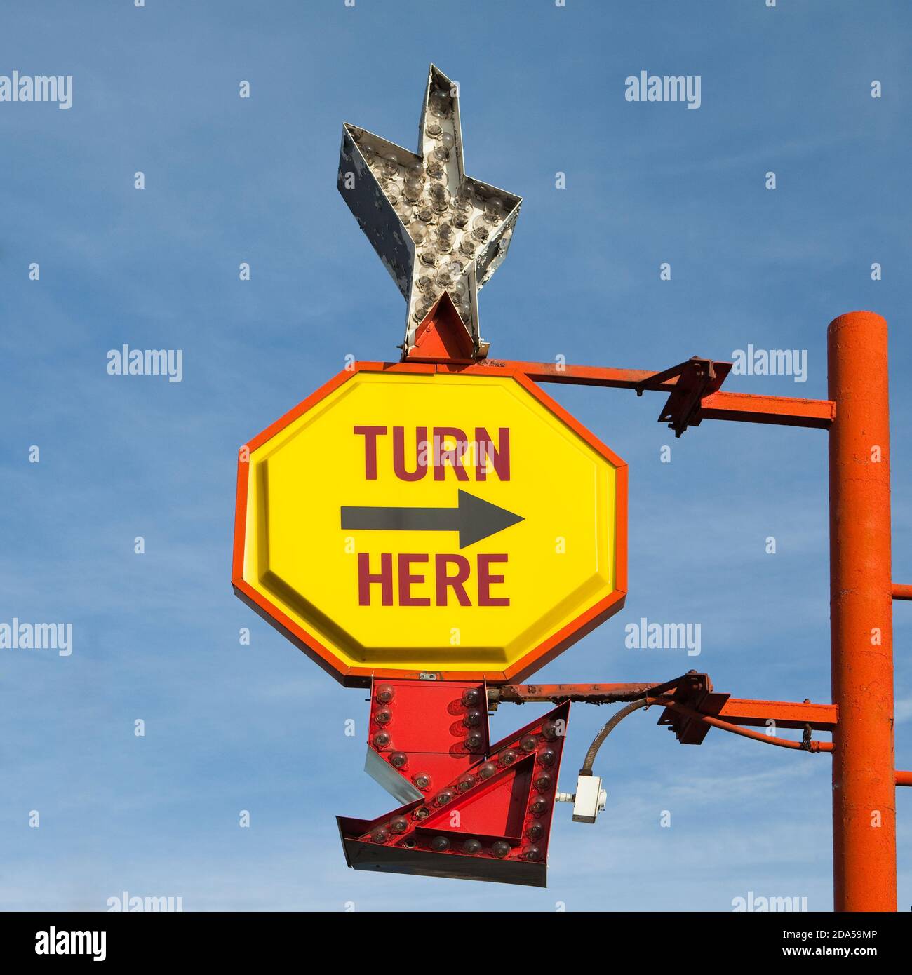 Turn Here, yellow traffic sign with arrow, on a gantry with a silver ...