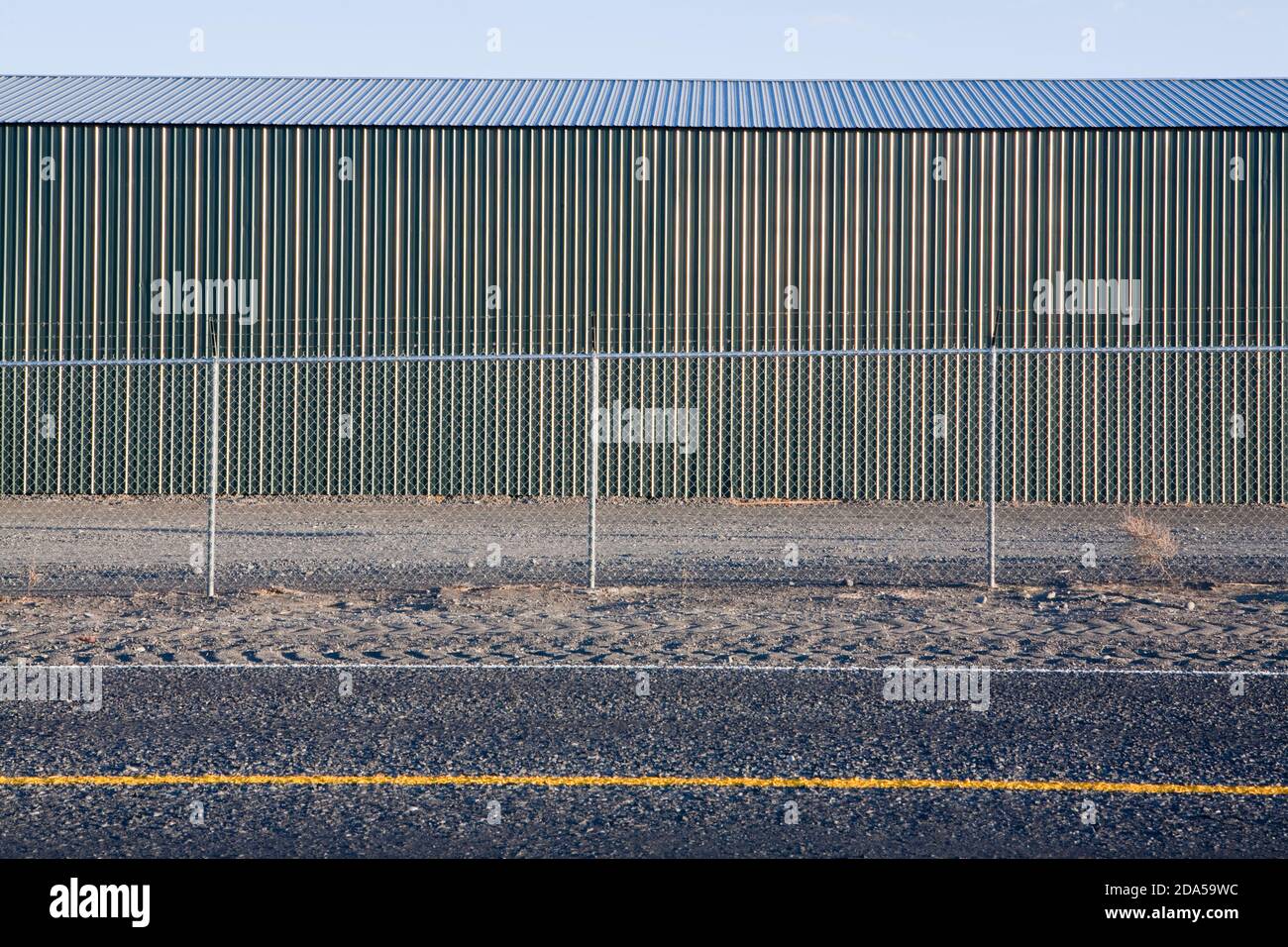 Corrugated iron building with a fence, by highway Stock Photo - Alamy