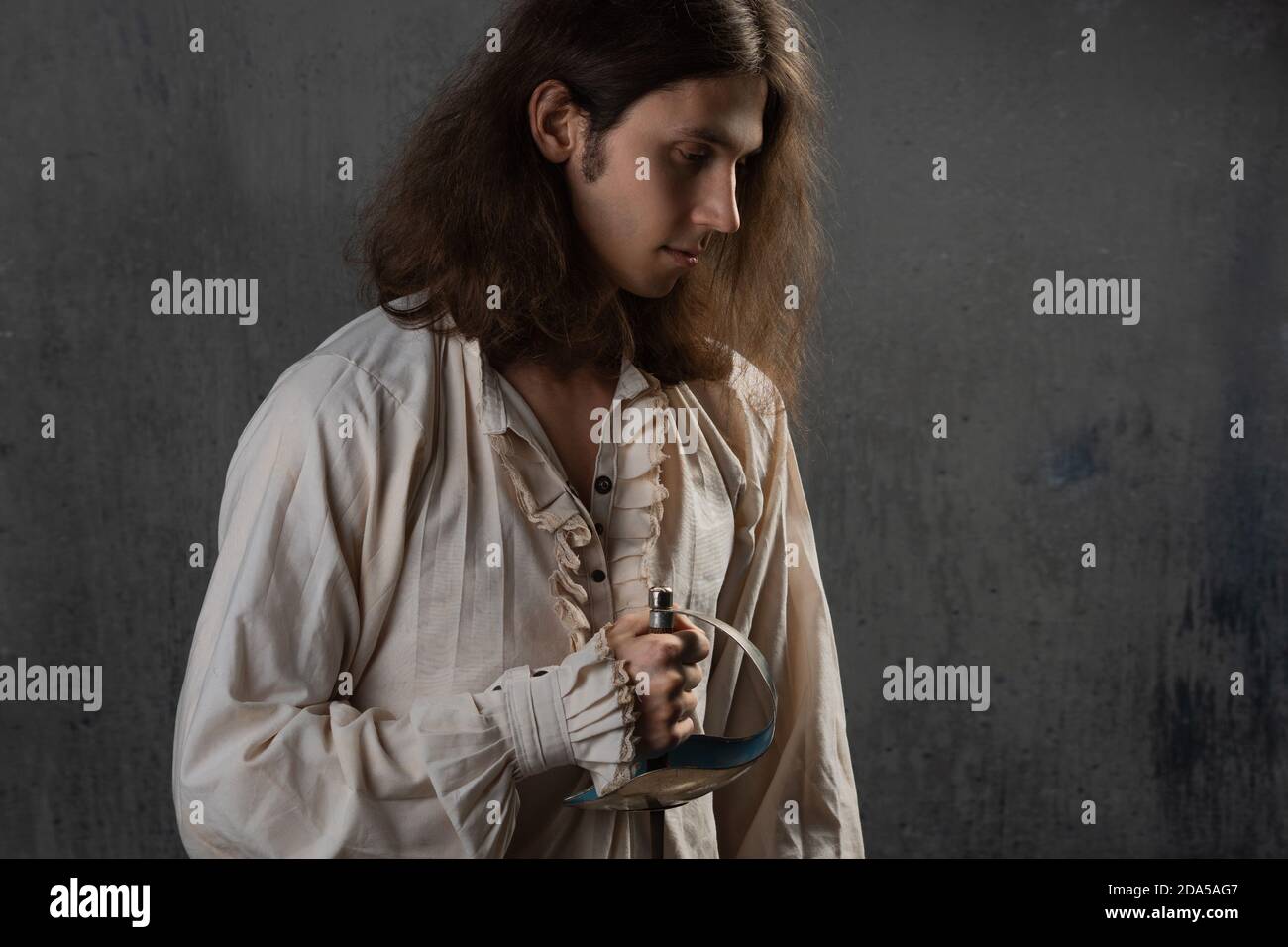 Romantic young man in a medieval costume with a sword in his hands, a ...