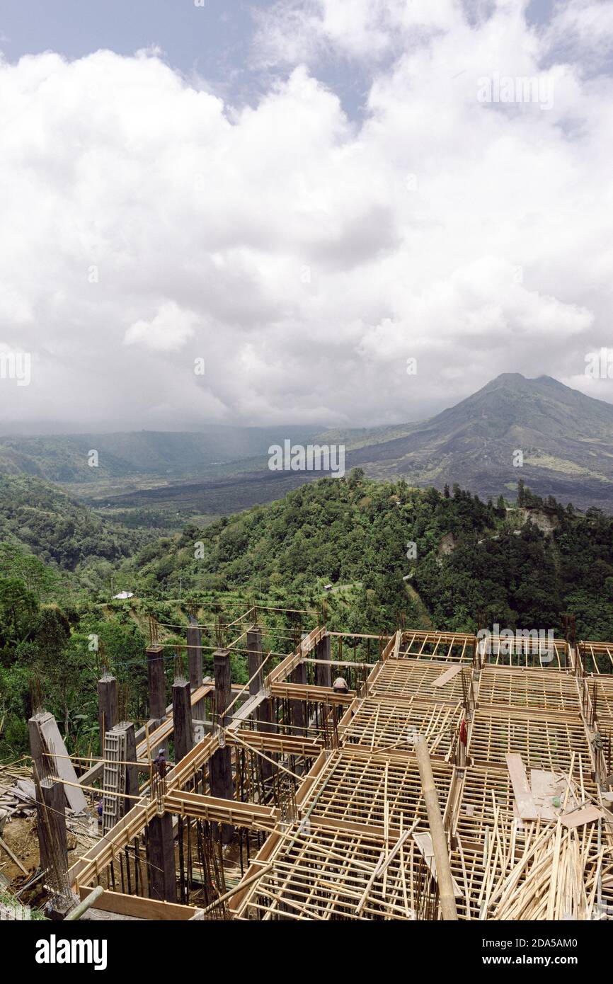 Construction site in Bali, building a wooden house with a volcano in ...