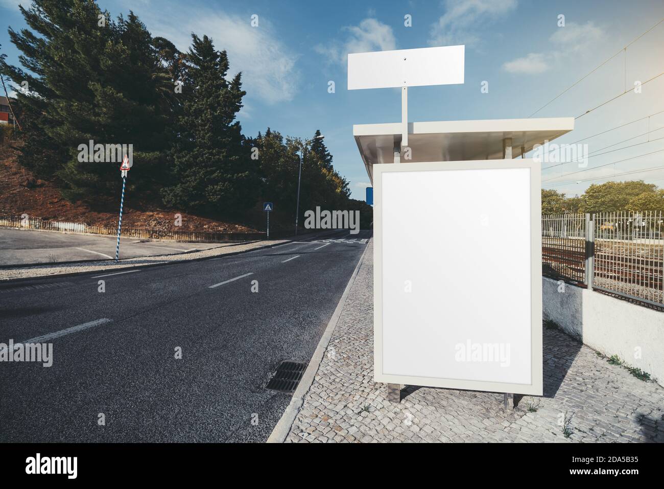 A bus stop near the road and a forest with a mockup of a blank advert ...