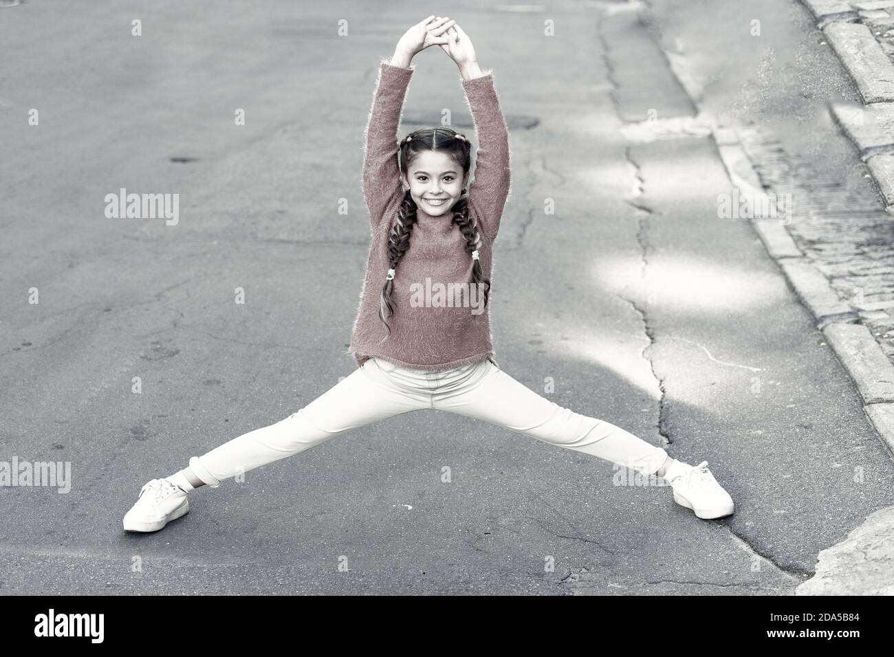 Improving flexibility through leg stretch training. Little girl ...