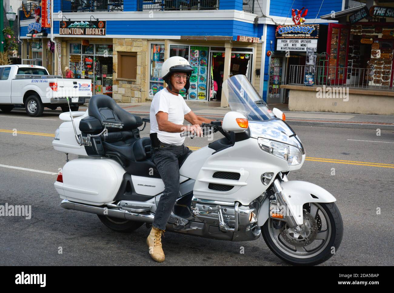 Smiling Grandpa wearing helmet on posh white motorcycle in downtown ...