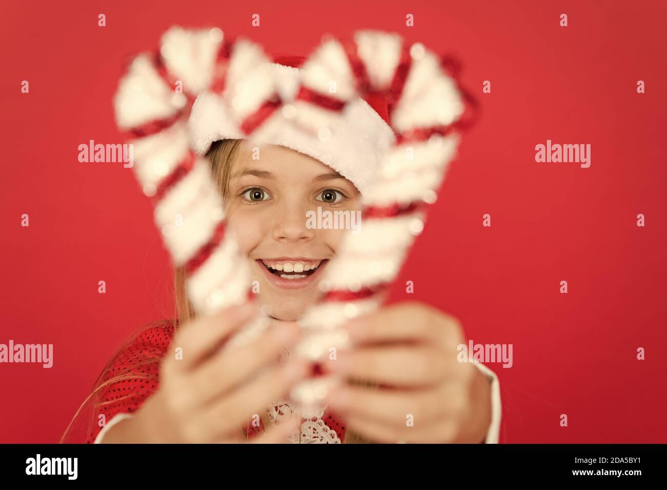 Girl looking through crossed candy canes close up defocused. Christmas ...