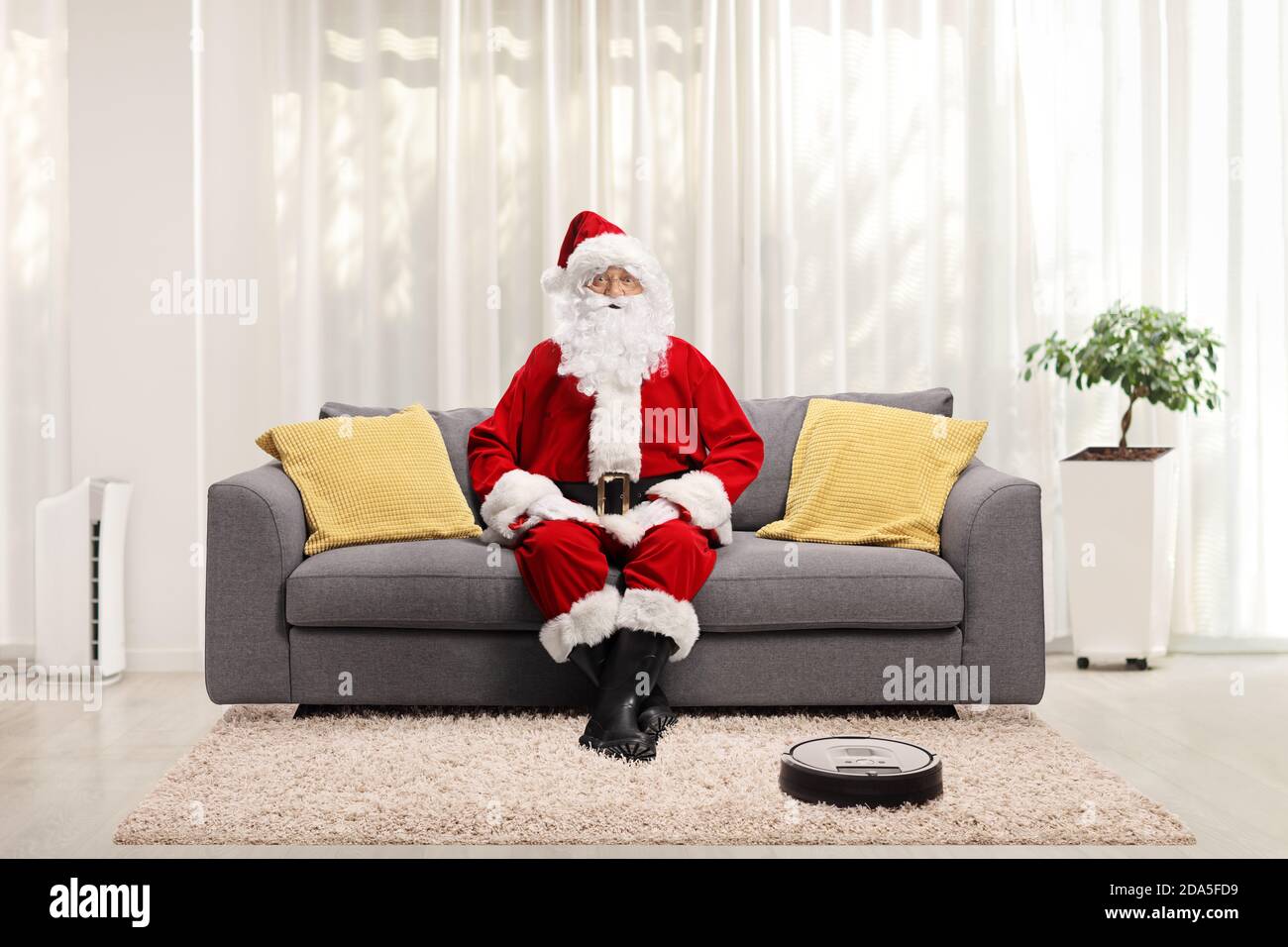 Full length portrait of santa claus at home sitting on a sofa and a ...