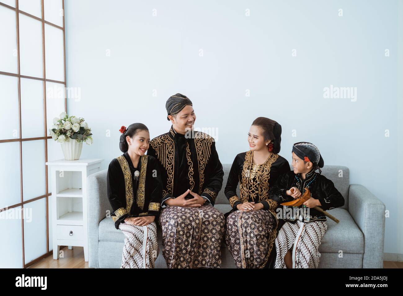 Portrait of a happy family wearing traditional Javanese clothes ...