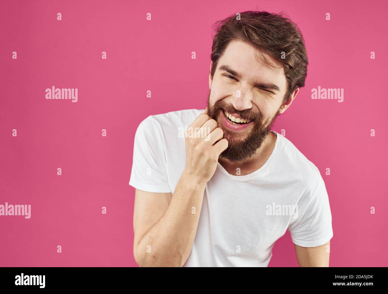 A cheerful guy with a beard laughs on a pink background and gestures ...