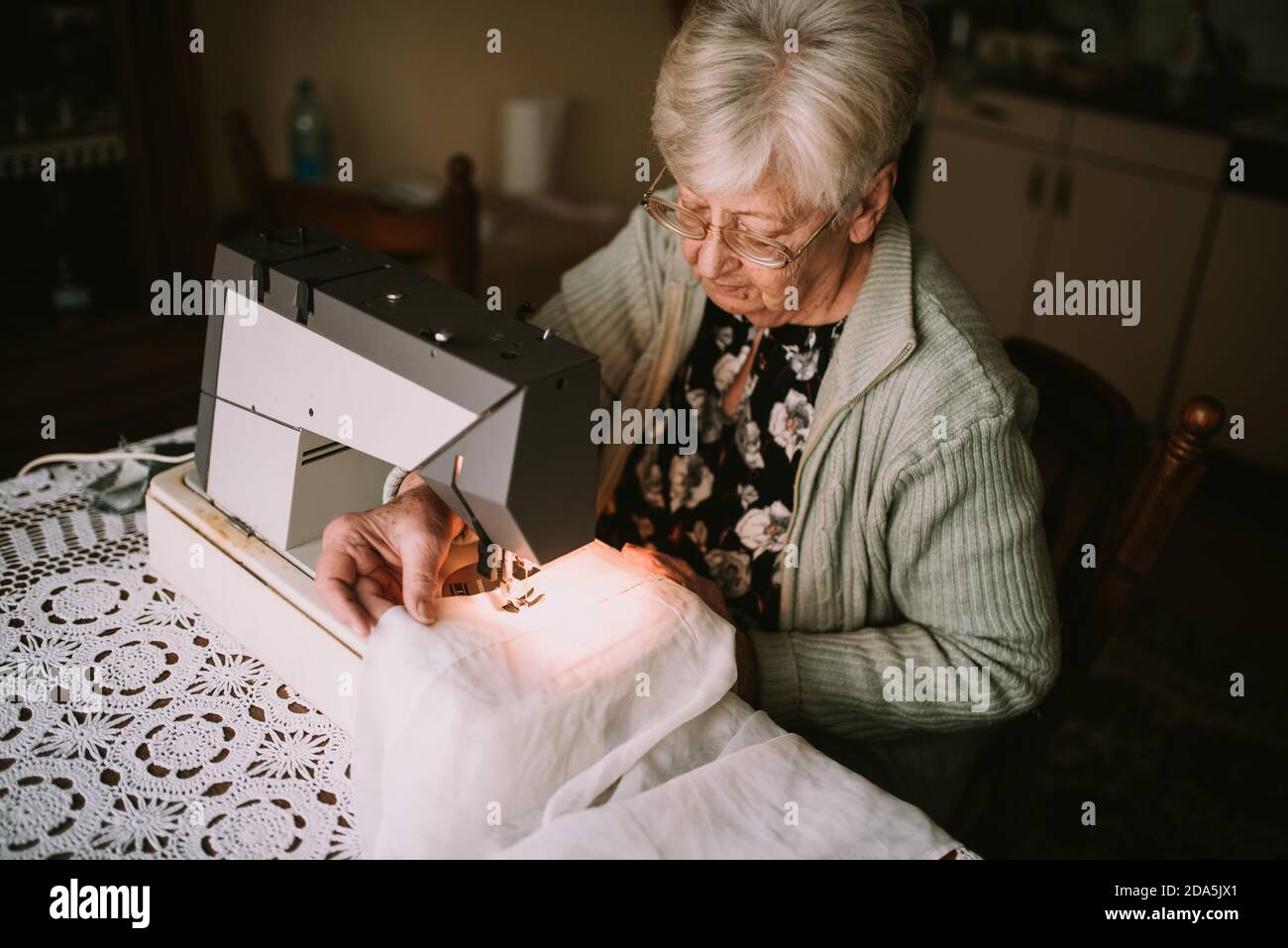 top view of a grandmother sewing on a machine in the living room ...
