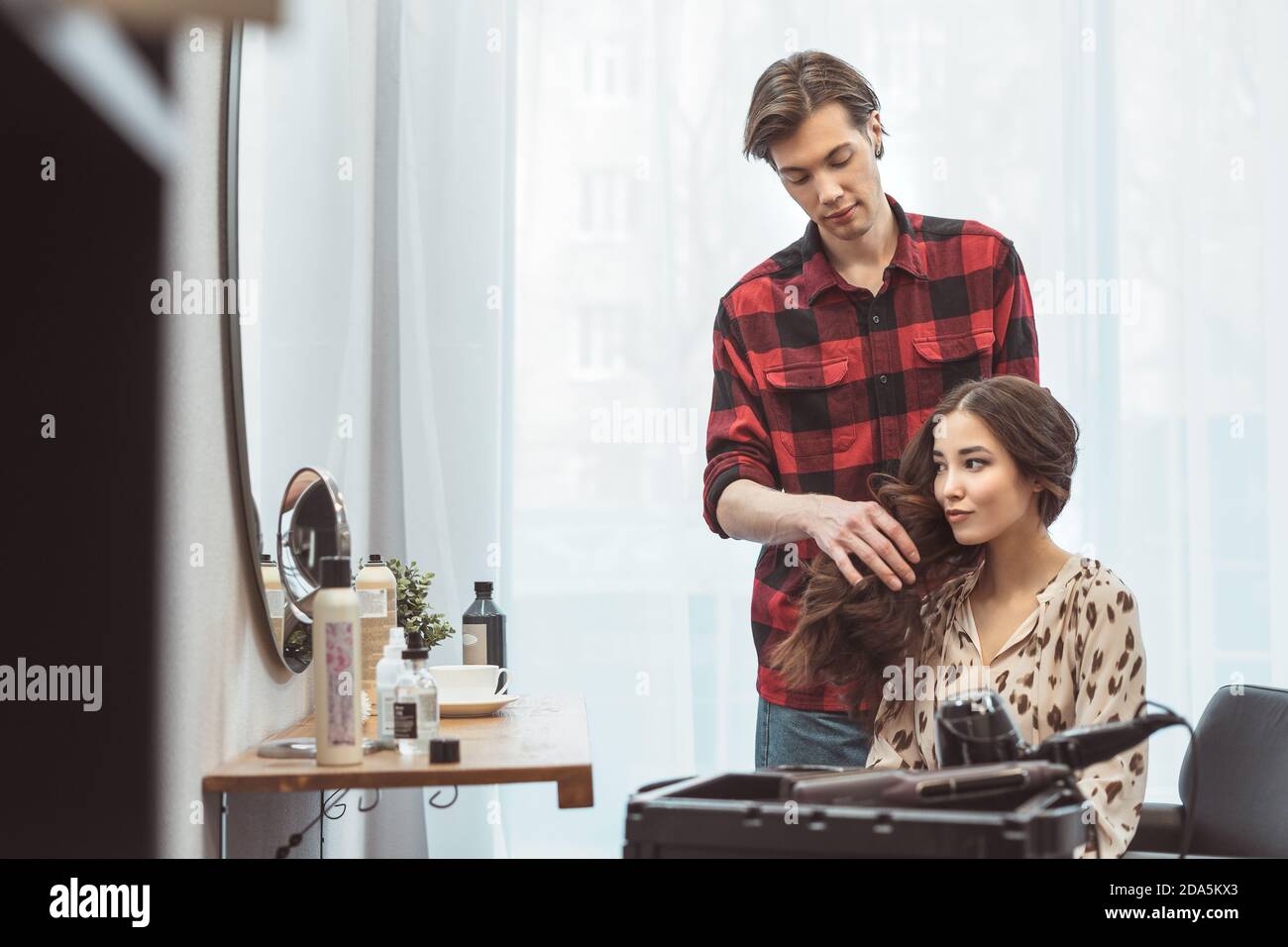 Stylist barber styling long hair for beautiful asian young woman in ...