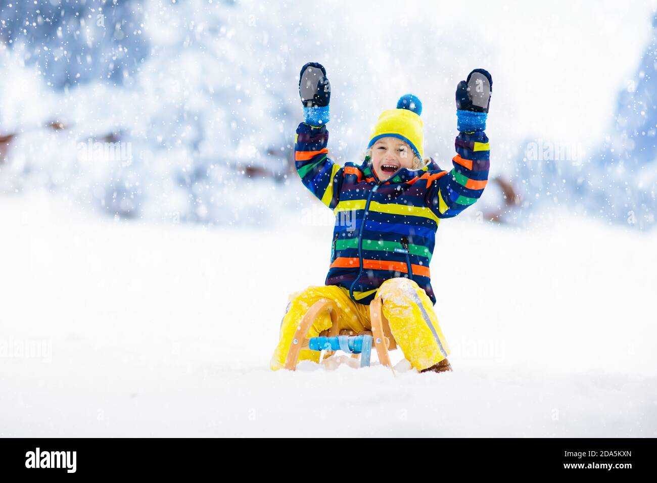 Little boy enjoying a sleigh ride. Child sledding. Toddler kid riding a ...