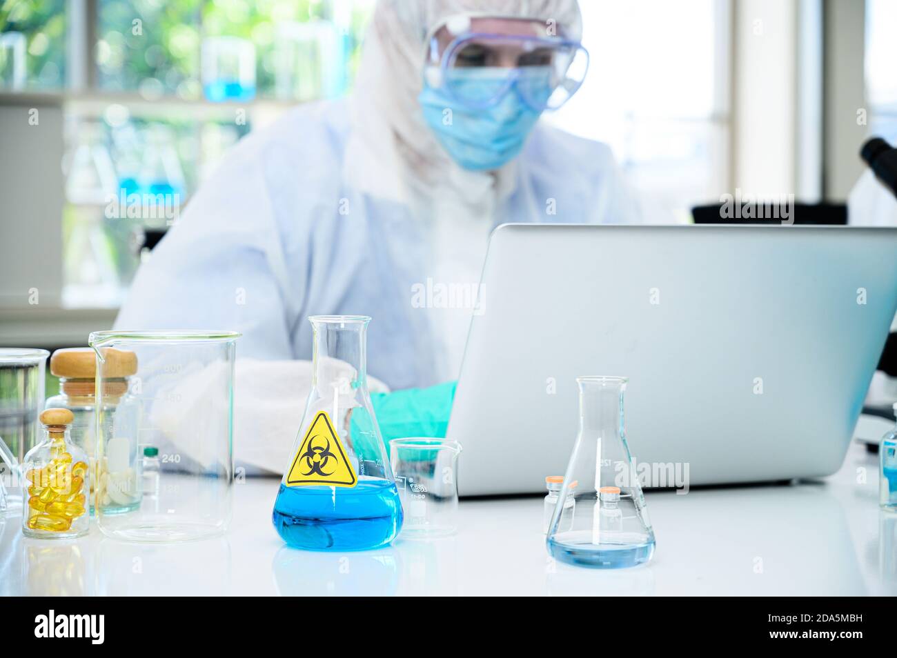 Lab equipment with blue liquid inside stand on the table with male ...