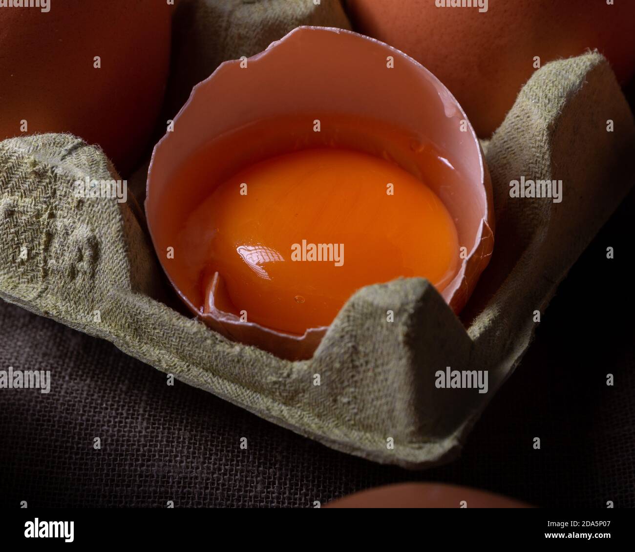 Egg yolk in a broken eggshell with a carton of eggs Stock Photo - Alamy