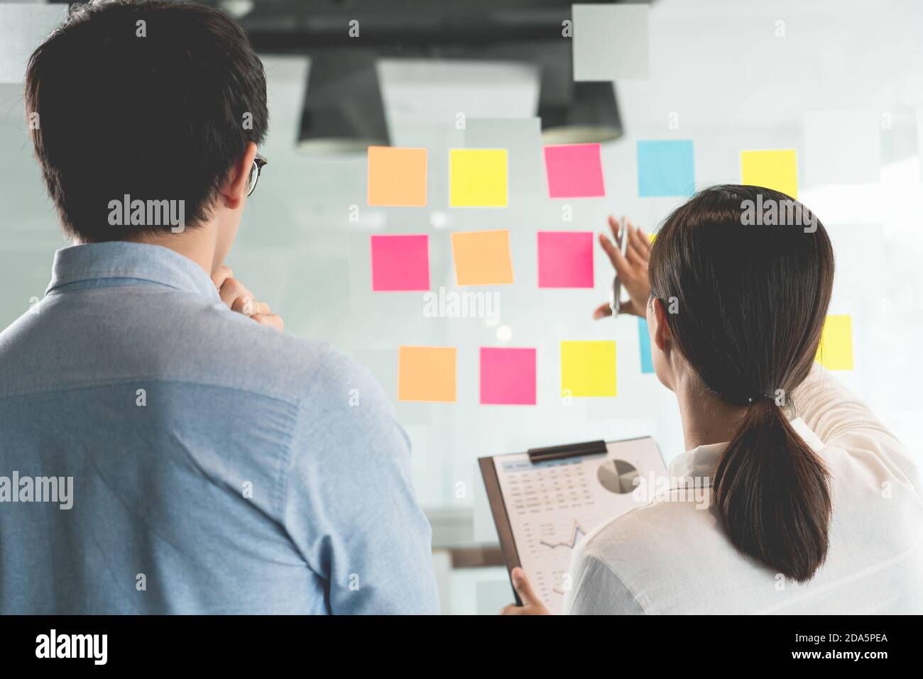 Business manager showing idea for her team and stick many memo paper on ...