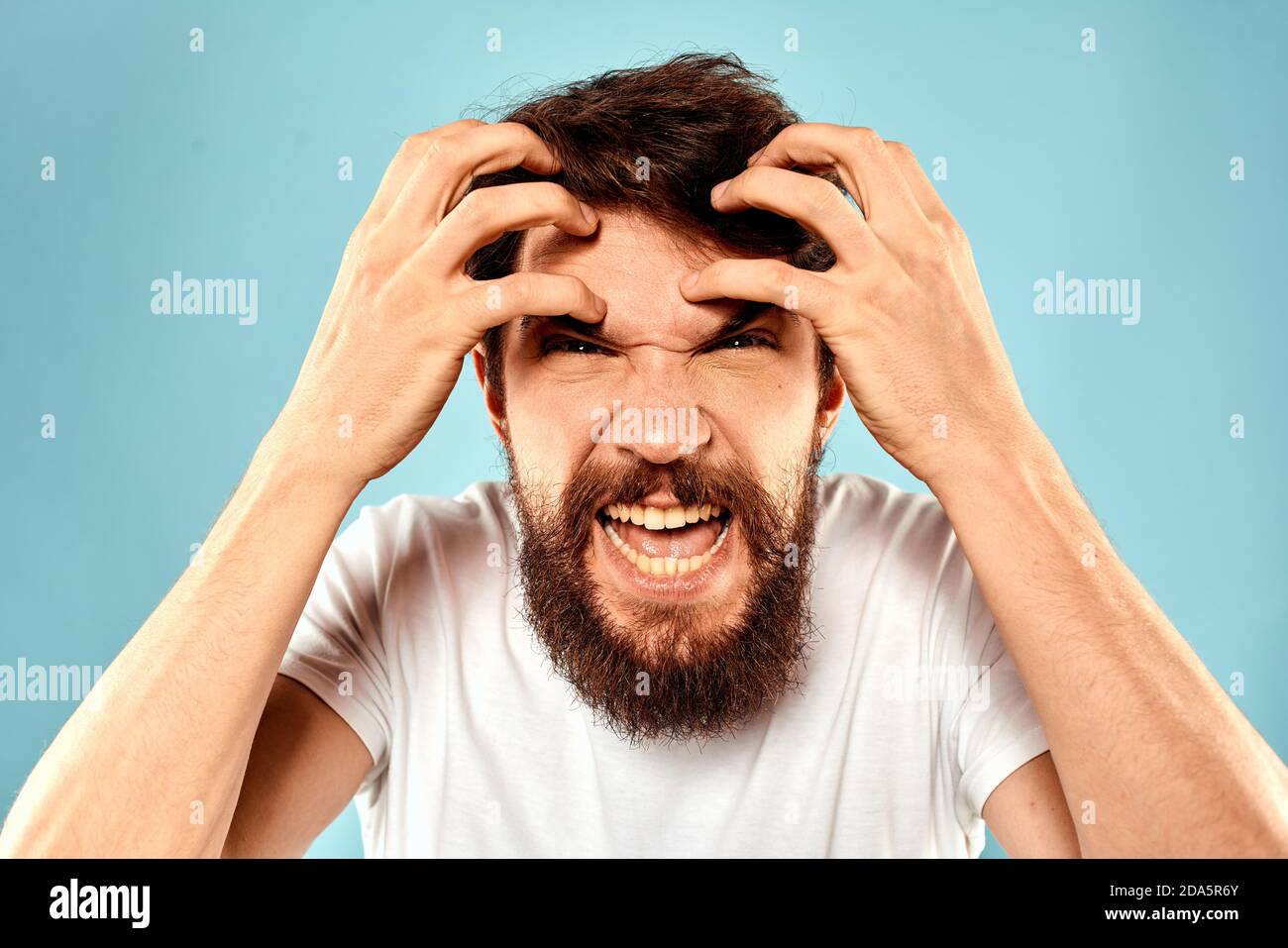 Bearded man in white T-shirt emotions gestures with hands displeased ...