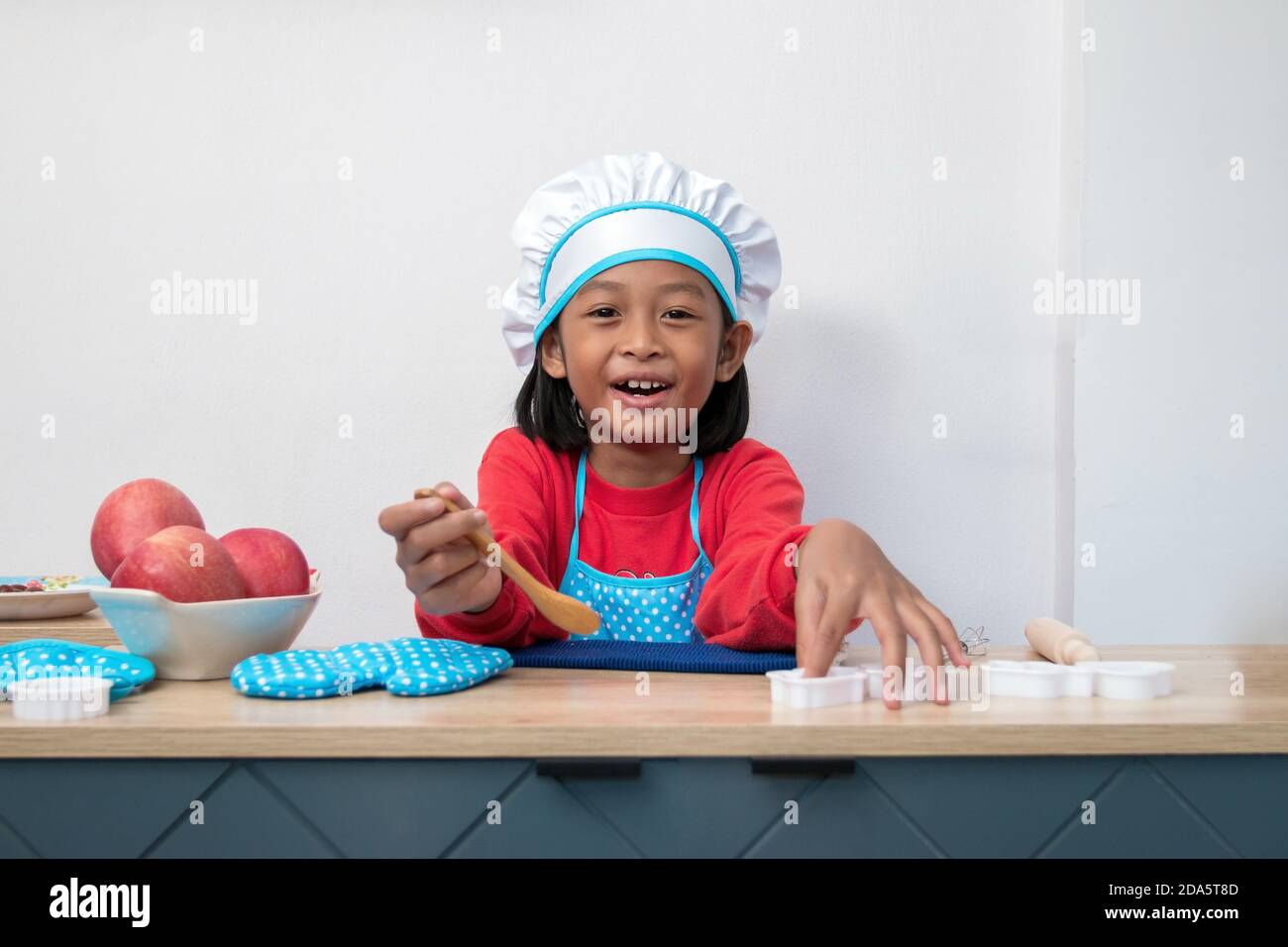 Cute girl in chef uniform and simulated cooking toys in the kitchen ...