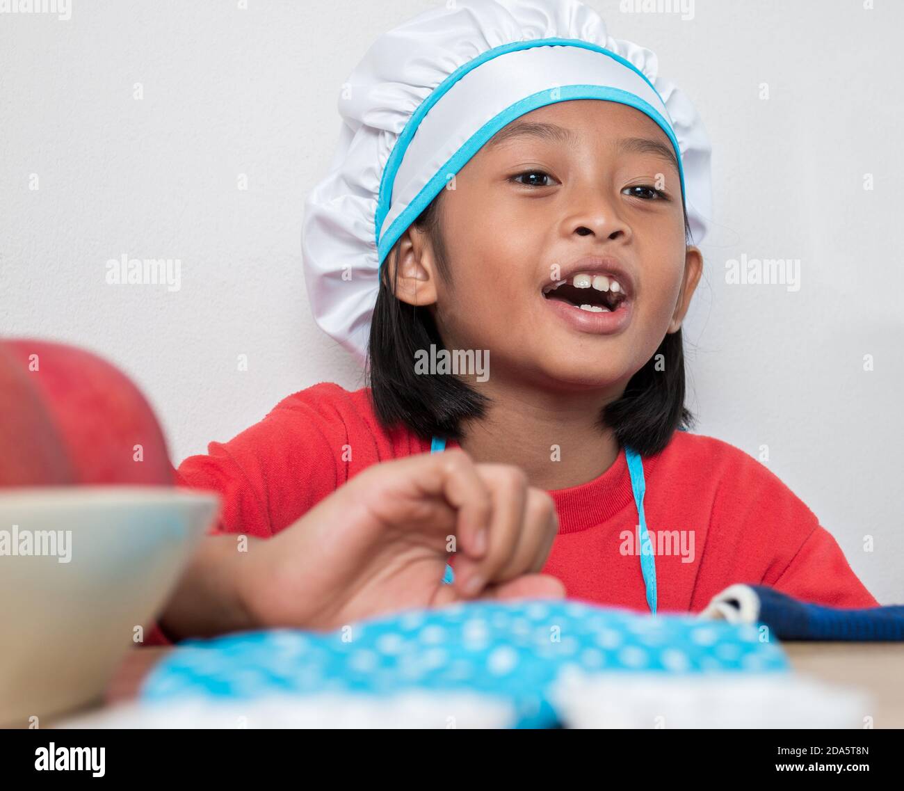 Cute girl in chef uniform and simulated cooking toys in the kitchen ...