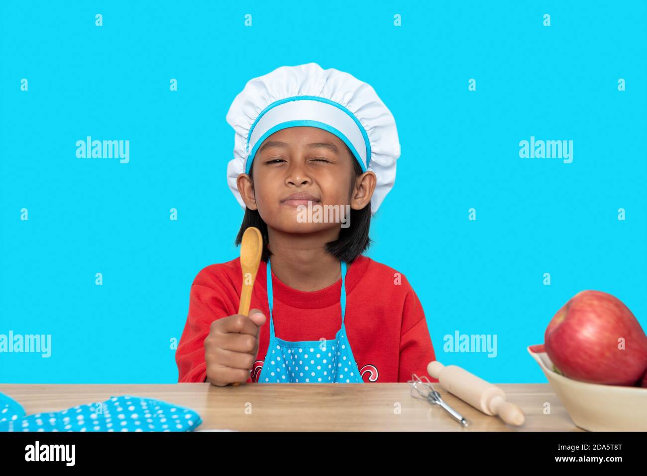 Cute girl in chef uniform and simulated cooking toys in the kitchen ...