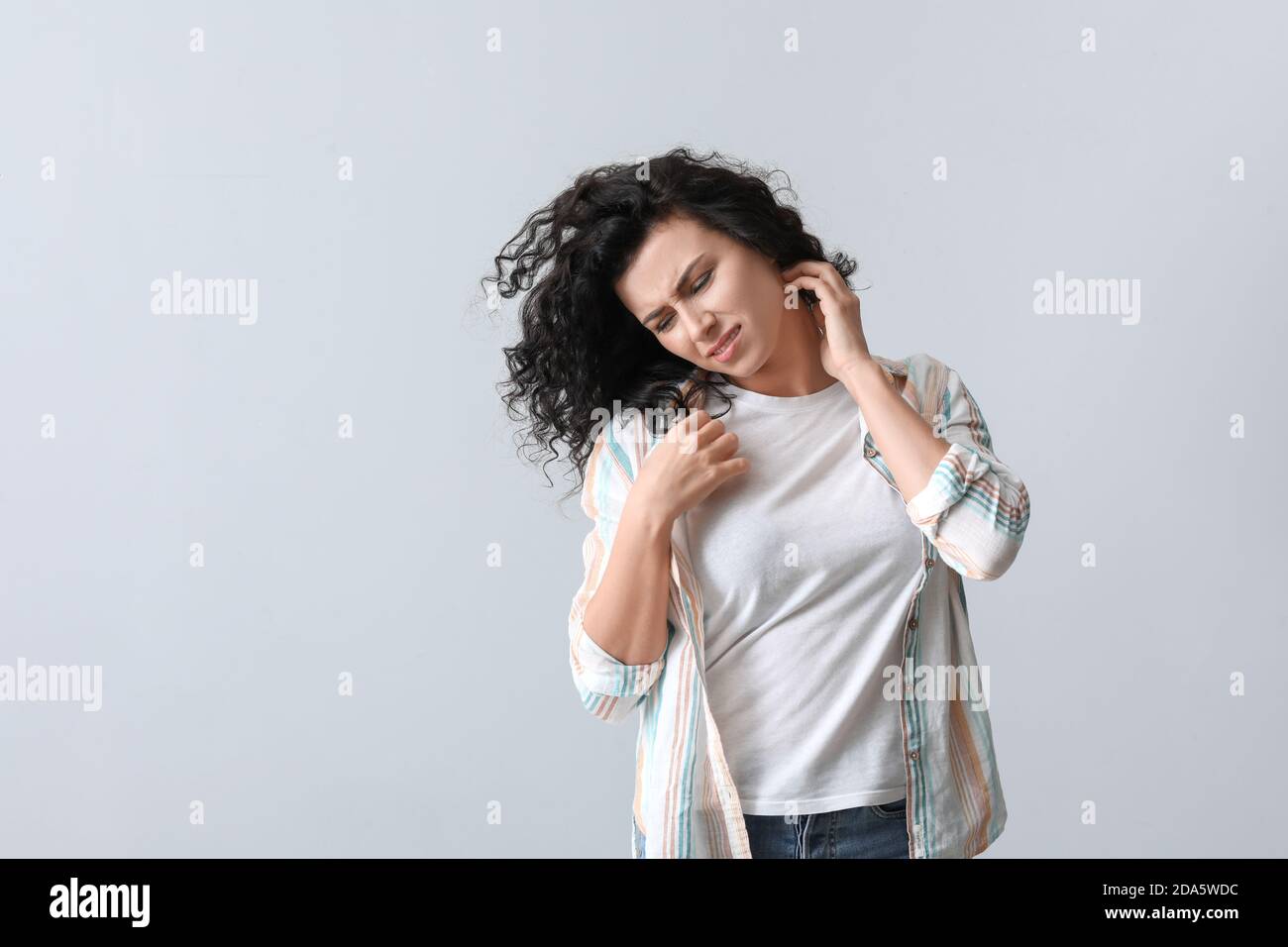 Allergic young woman scratching herself on grey background Stock Photo ...