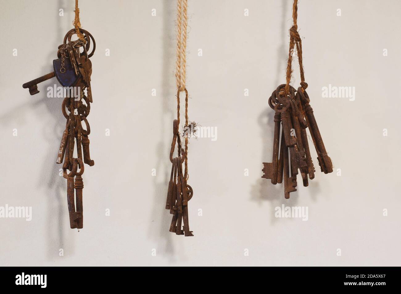 old rusty metal keys hanging on rope over white wall Stock Photo - Alamy