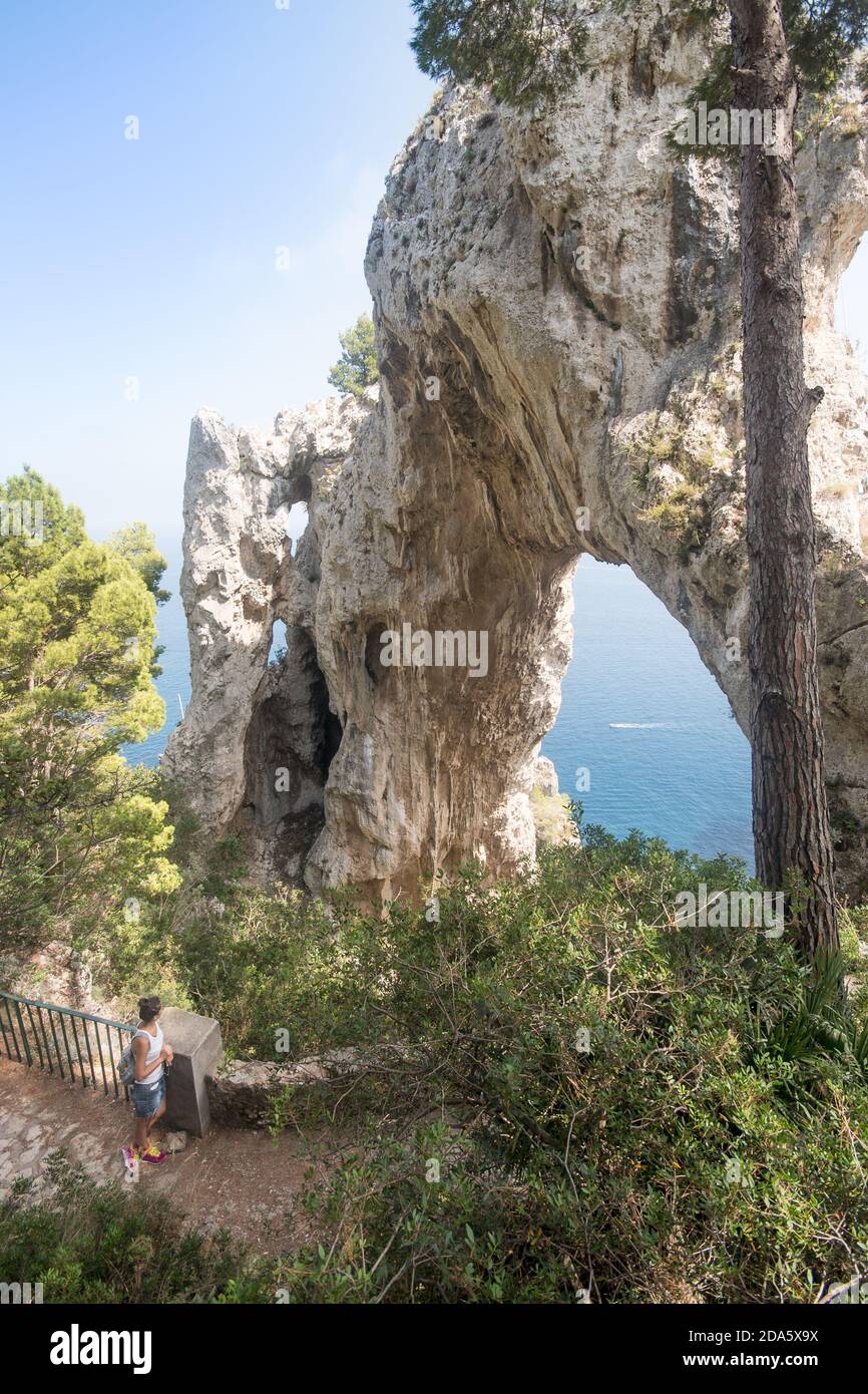 View of a natural rock arch with the sea in the background and a woman ...