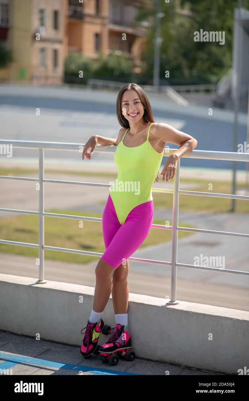 Sporty girl. Girl in roller-skates and bright sportswear leaning on ...