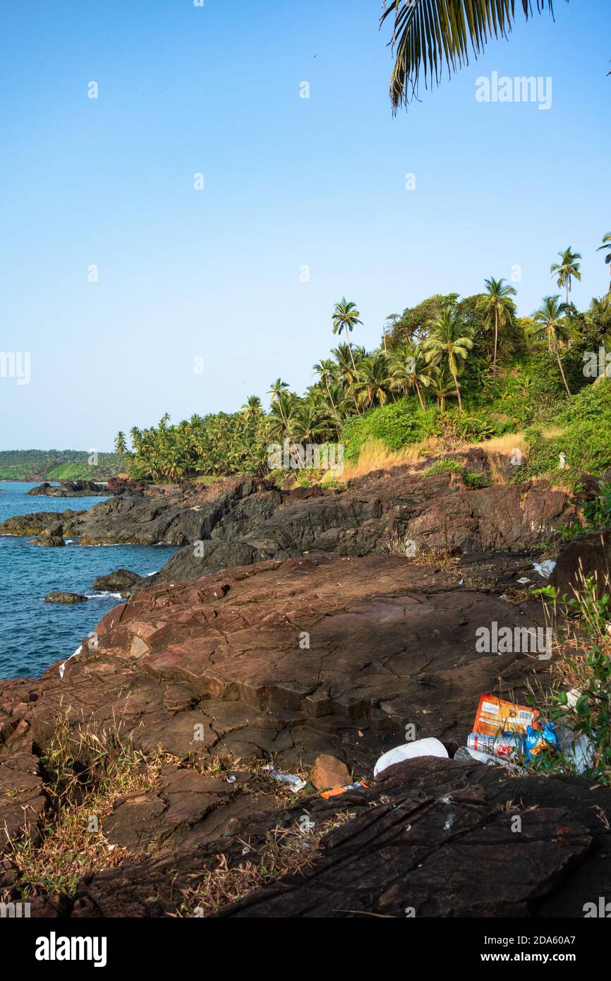 Plastic waste garbage thrown on the scenic rocky shoreline by tourists ...