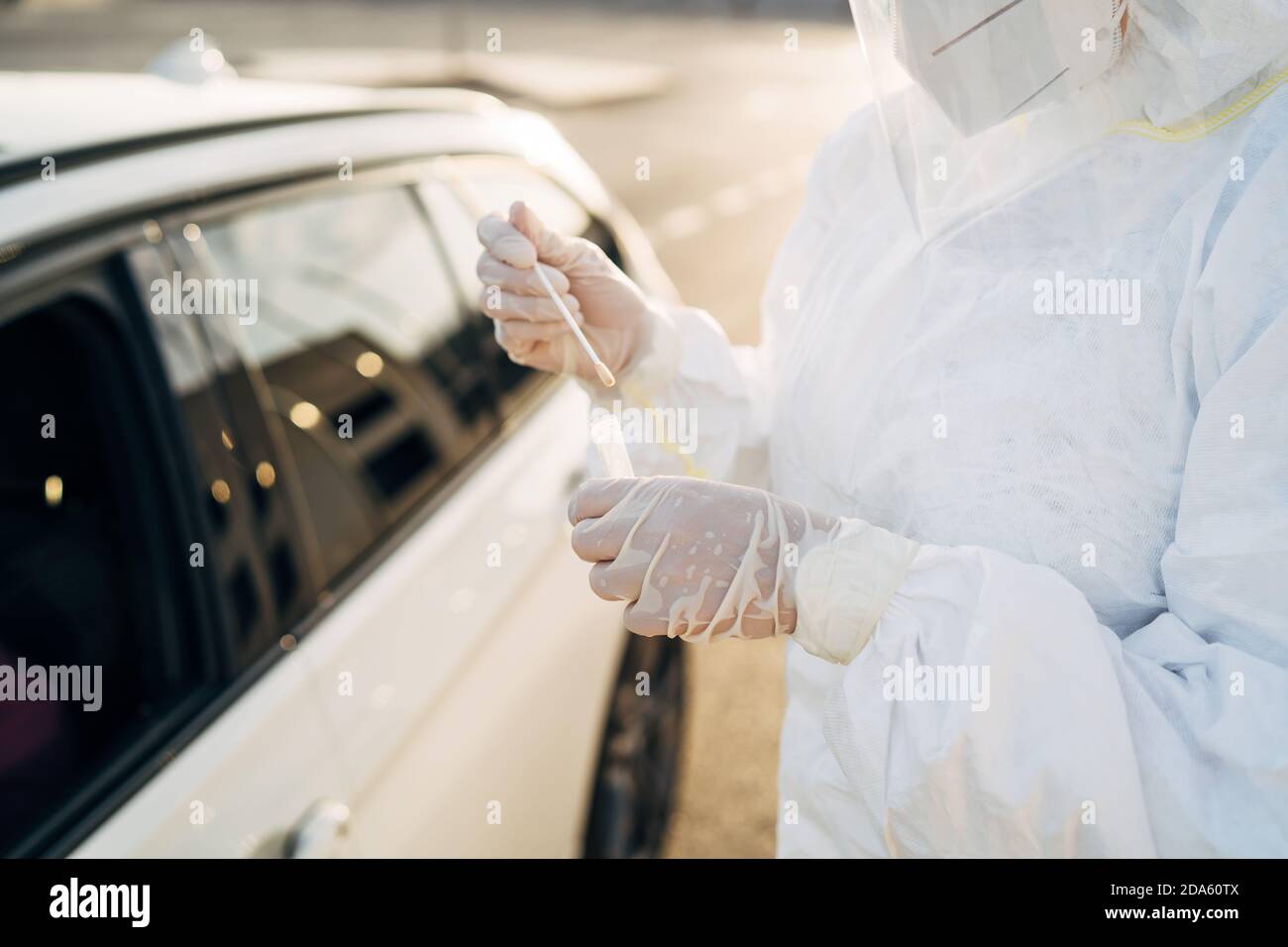 Doctor doing a PCR test COVID-19 on a patient through the car window ...