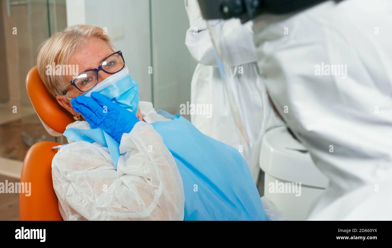 Patient with protection suit touching face having toothache at ...