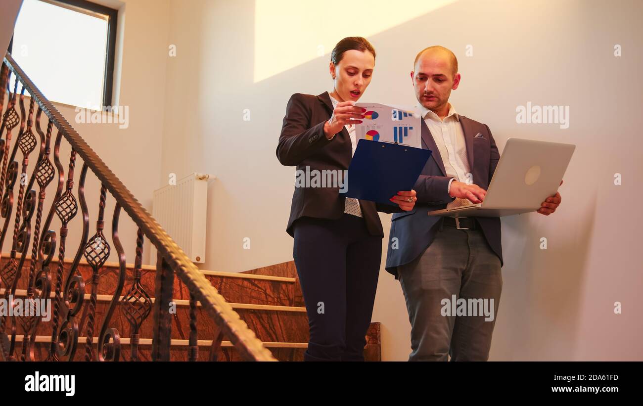 Businesswoman talking with corporate executive manager on staircase of ...