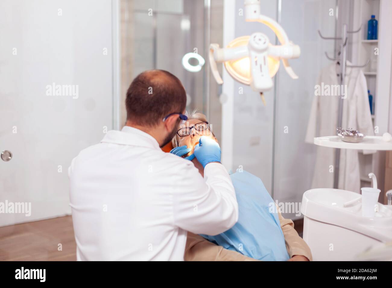 Denstis in cabinet repairing senior patient tooth in dental clinic ...