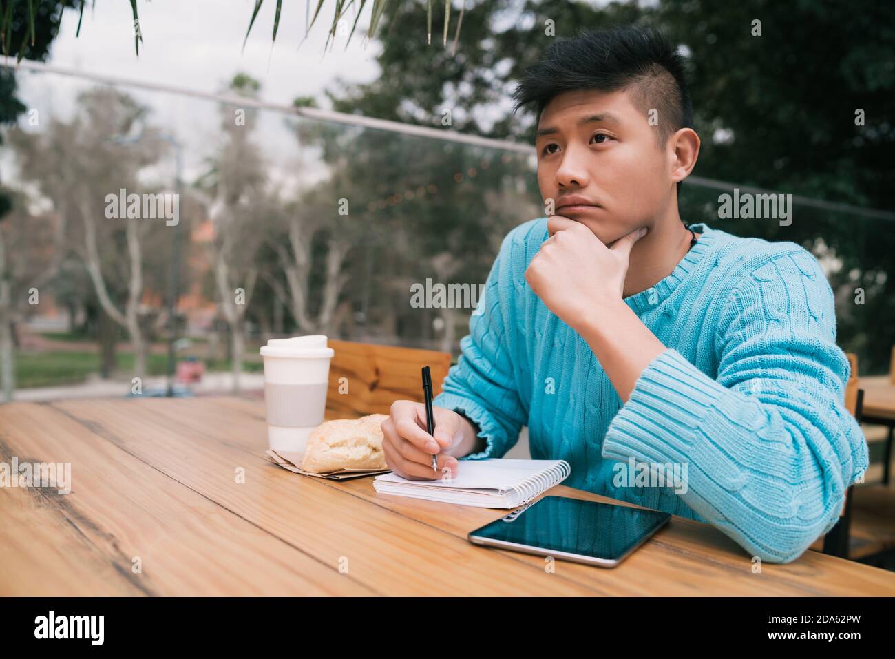 Asian man studying in coffee shop Stock Photo - Alamy