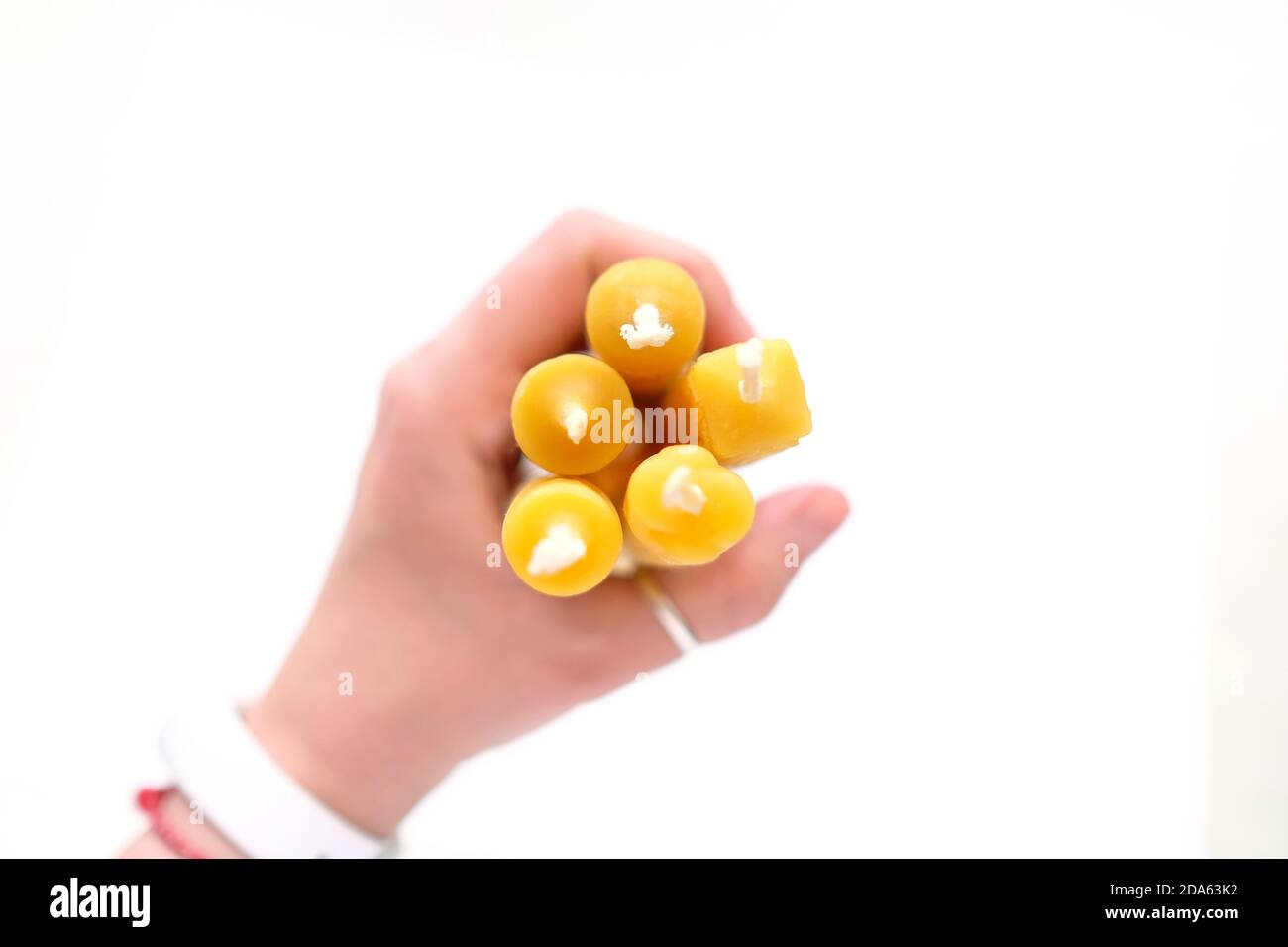 Hold several large candles in your left hand. Blurred edges, on white ...