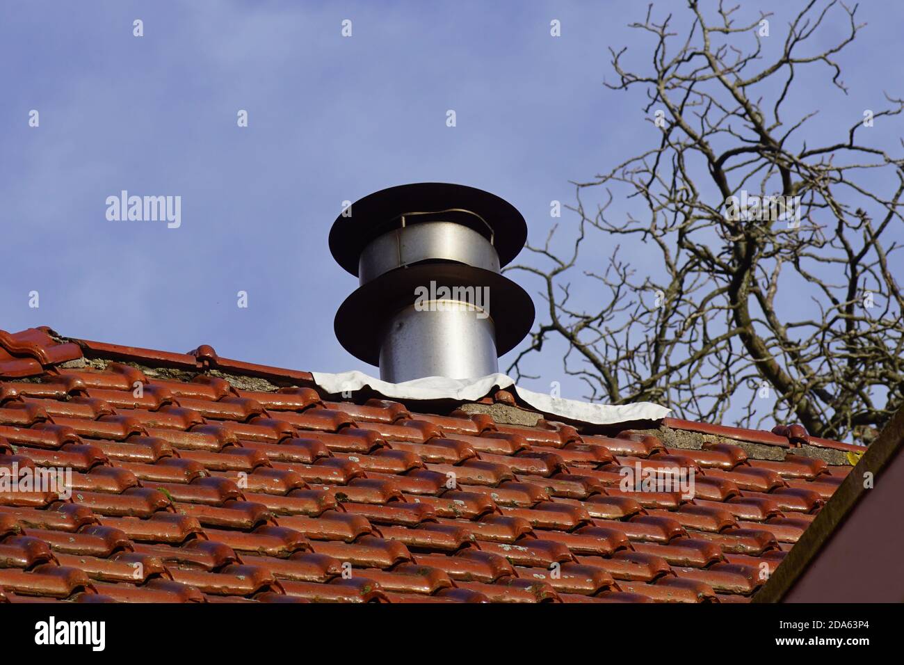 Zinc roof gutter full of autumn leaves under red glazed roof tiles ...