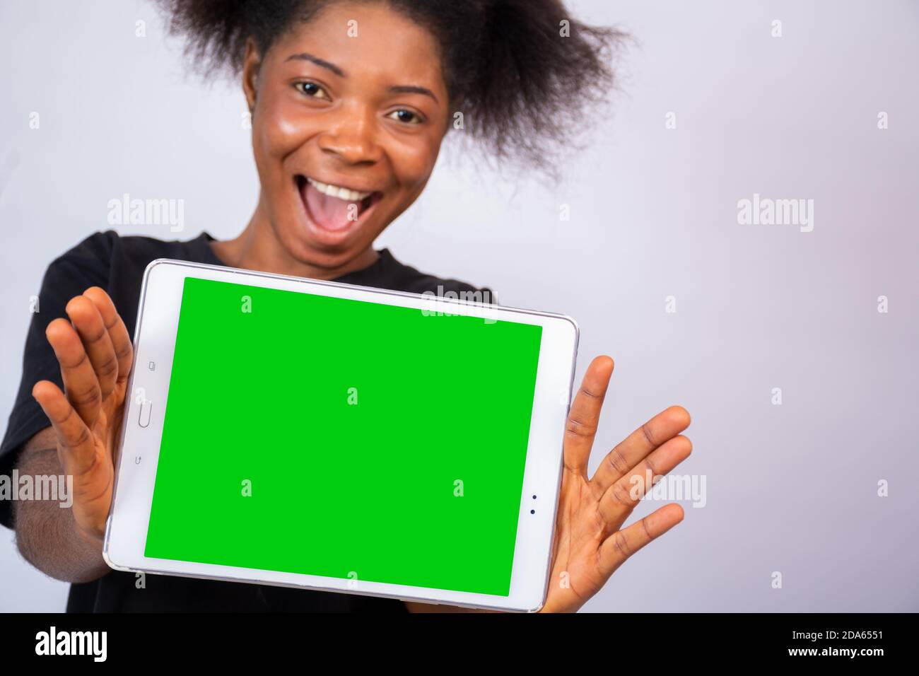 close up of an excited young african lady holding a tablet computer ...