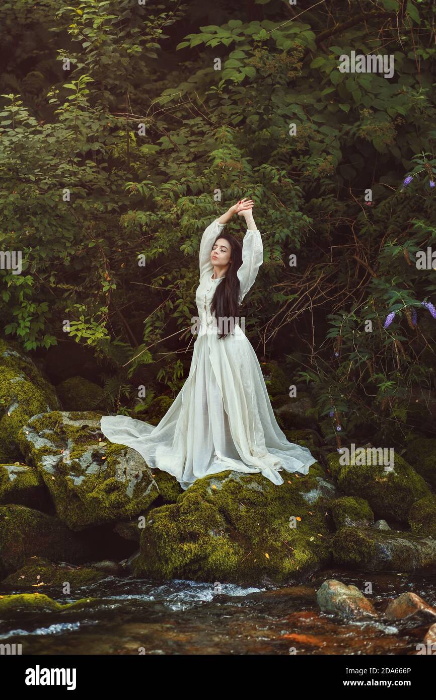 Beautiful romantic woman posing among green leaves Stock Photo - Alamy