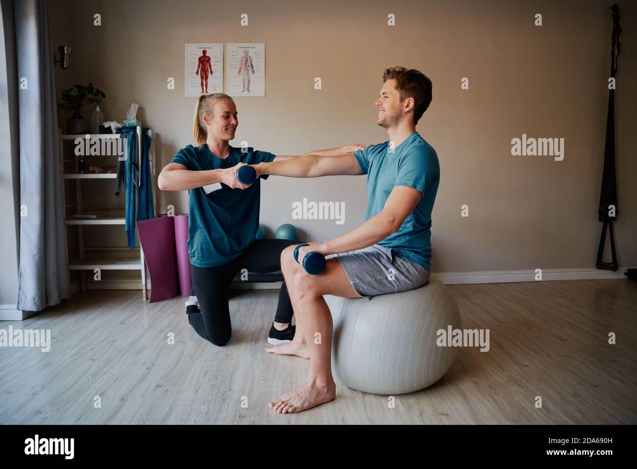 Female nurse helping young man doing stretching exercise in hospital ...