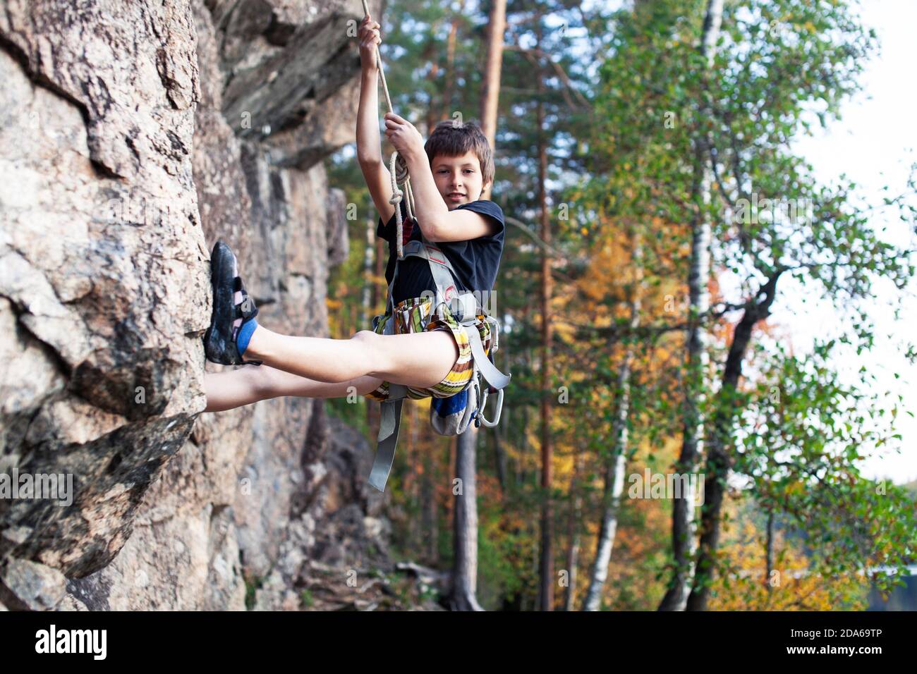 cute teen kid climbing on rock with insurance, lifestyle sport people ...