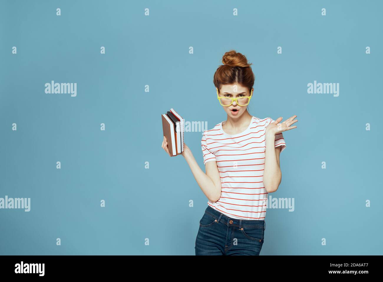 Female student with books in hands on a blue background and yellow ...