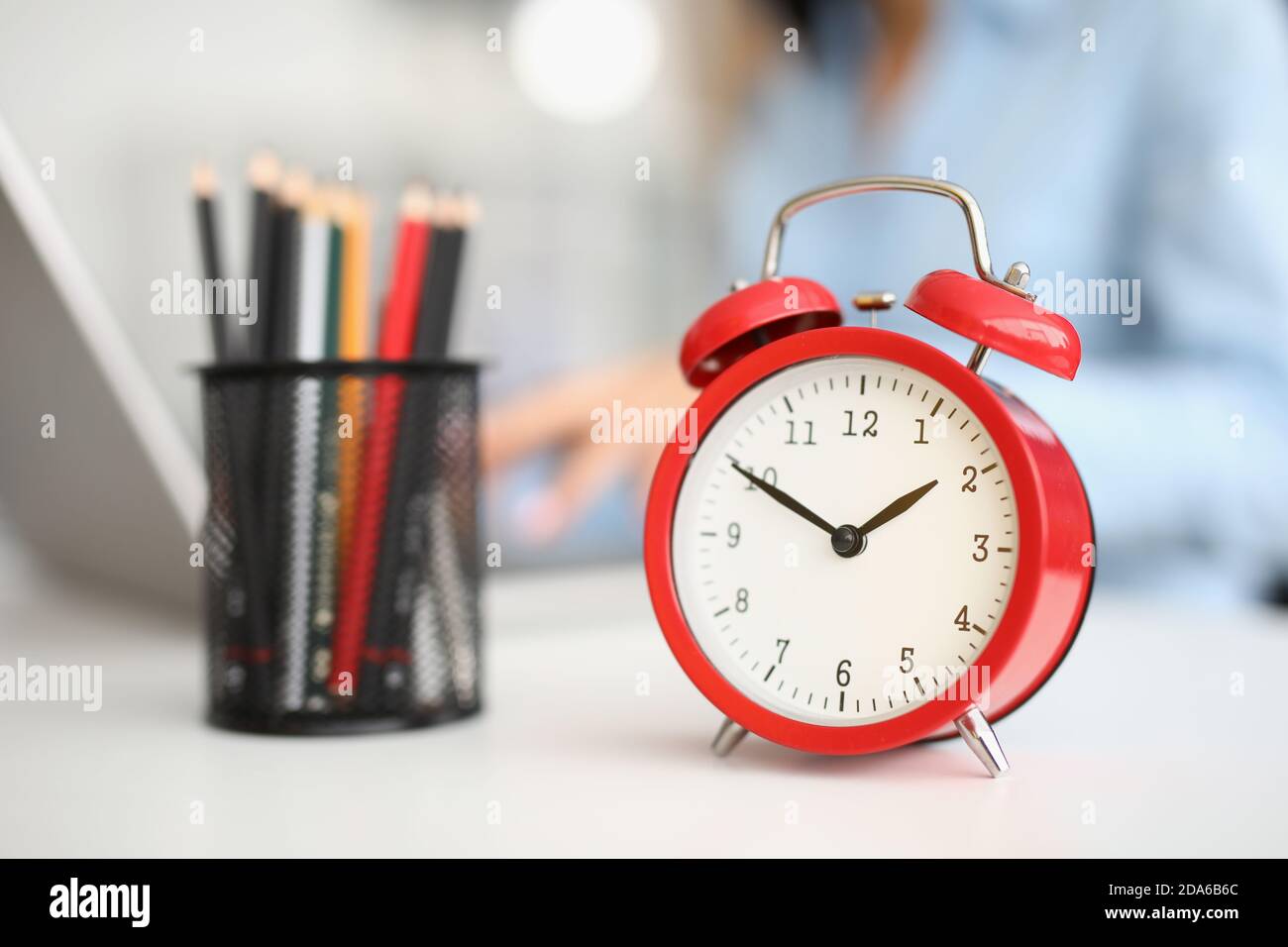 On desktop red alarm clock and colored pencils Stock Photo - Alamy