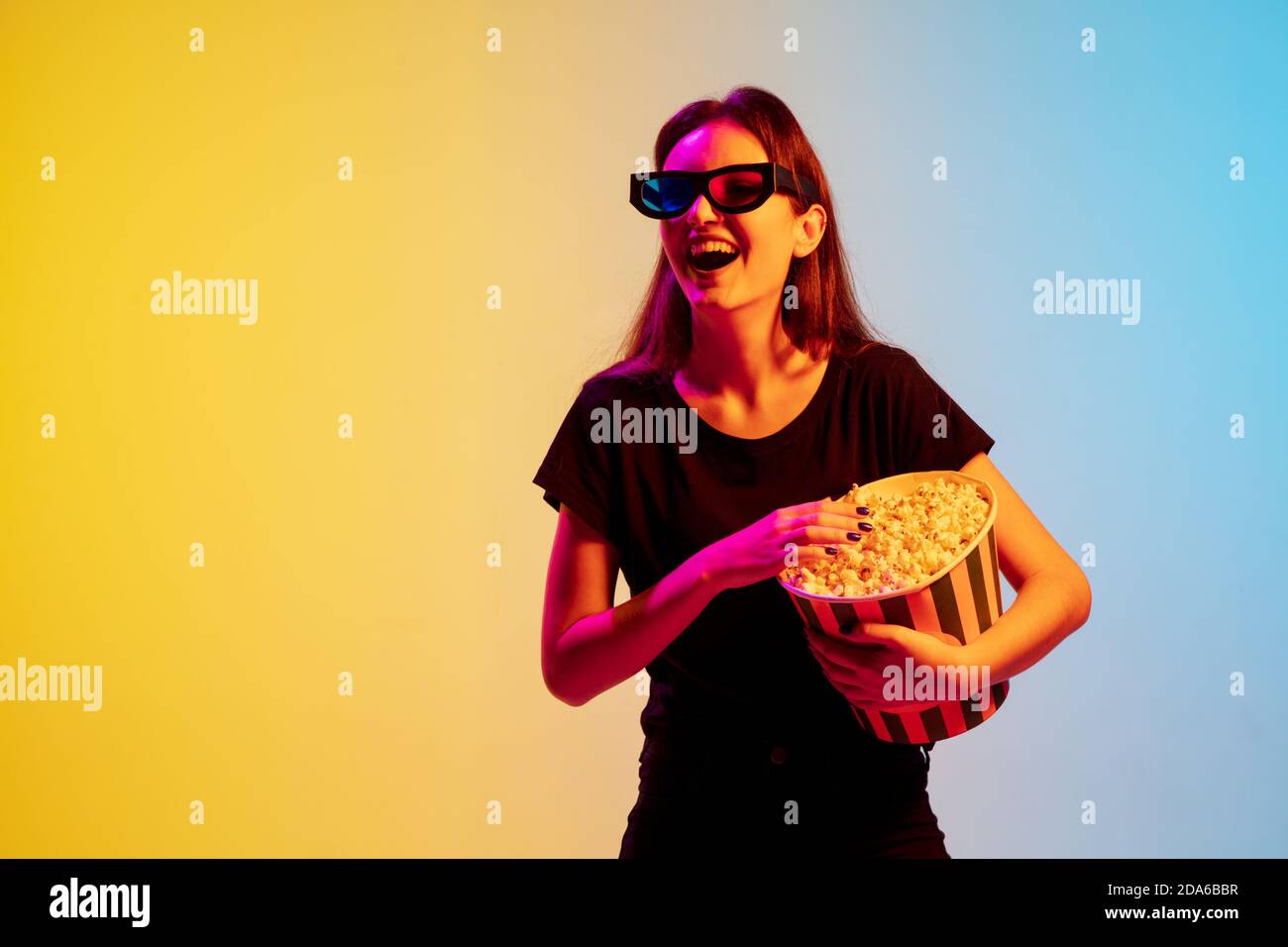 Laughting. Young caucasian woman with bunch of popcorn on gradient blue ...