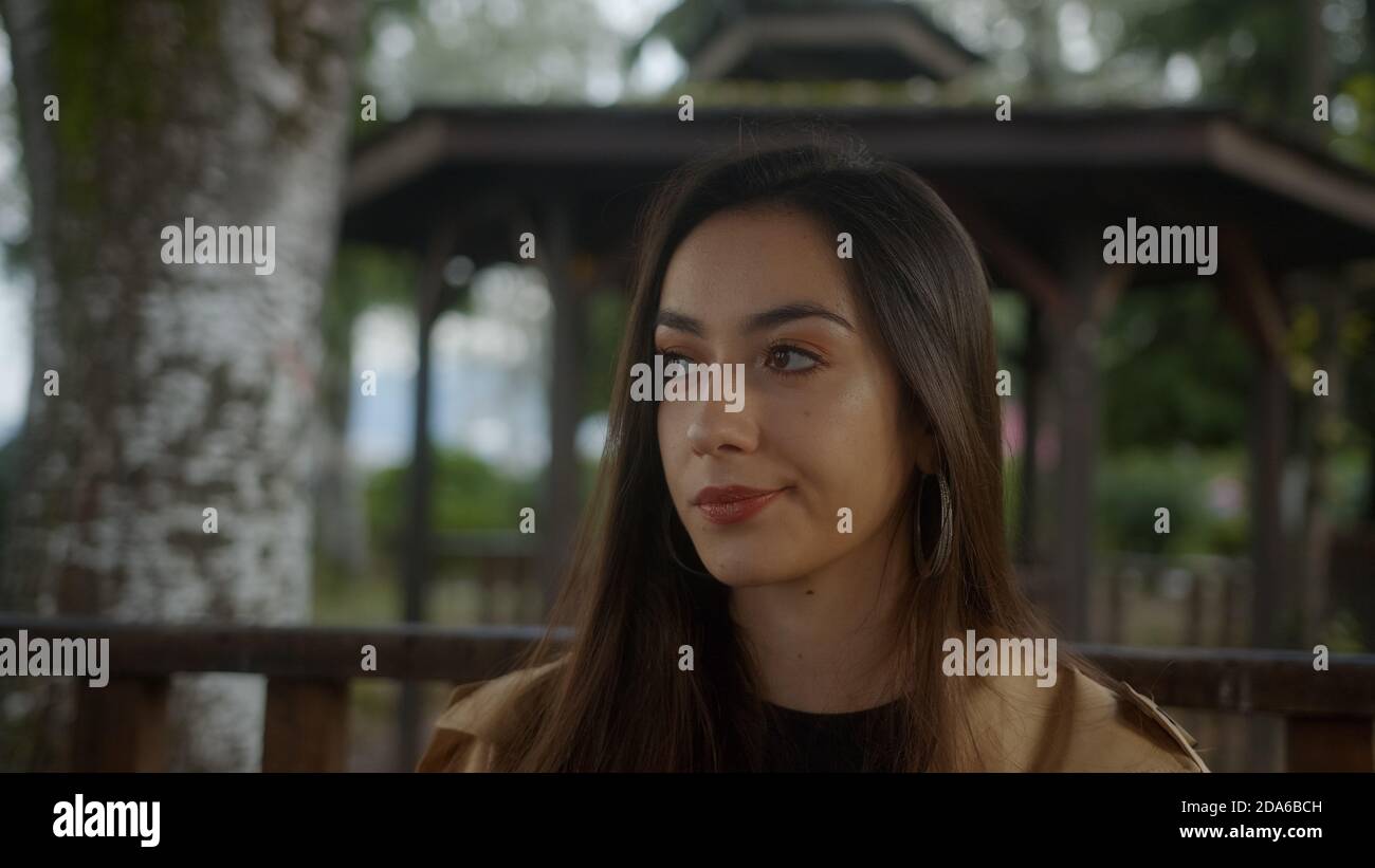 Portrait of charming pretty woman sitting in the gazebo, looking at ...