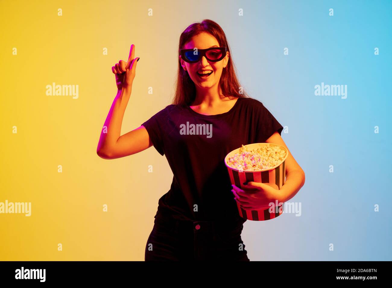 Pointing. Young caucasian woman with bunch of popcorn on gradient blue ...