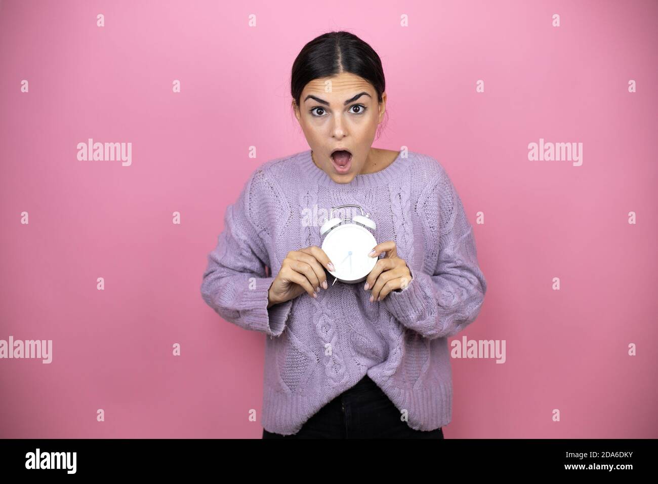 Beautiful woman wearing a casual violet sweater over pink background ...