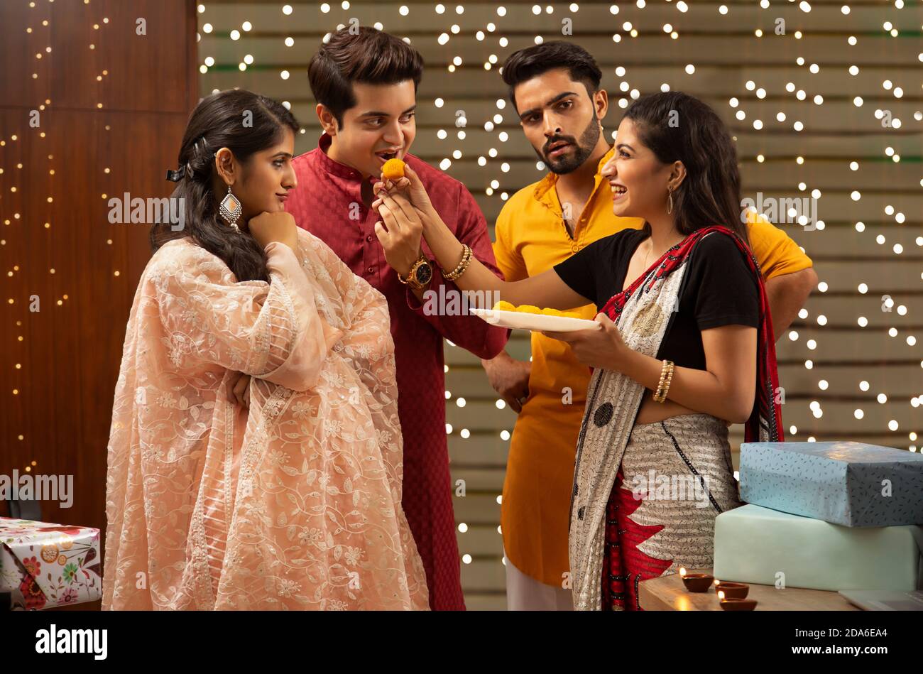 A YOUNG WOMAN GIVING LADDU TO A MALE COLLEGUE WITH OTHER FRIENDS ...